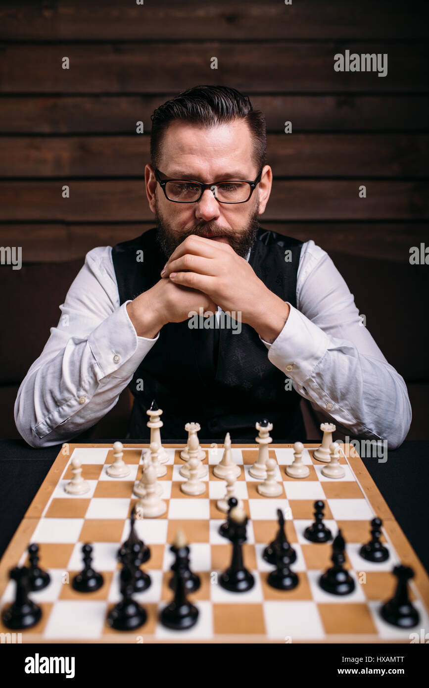 Pensive male chess player in glasses thinking about game strategy ...