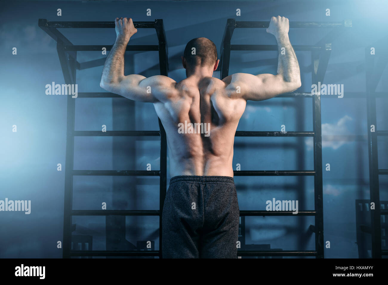 Strong sportsman training on horizontal bar in gym, back view. Muscle ...