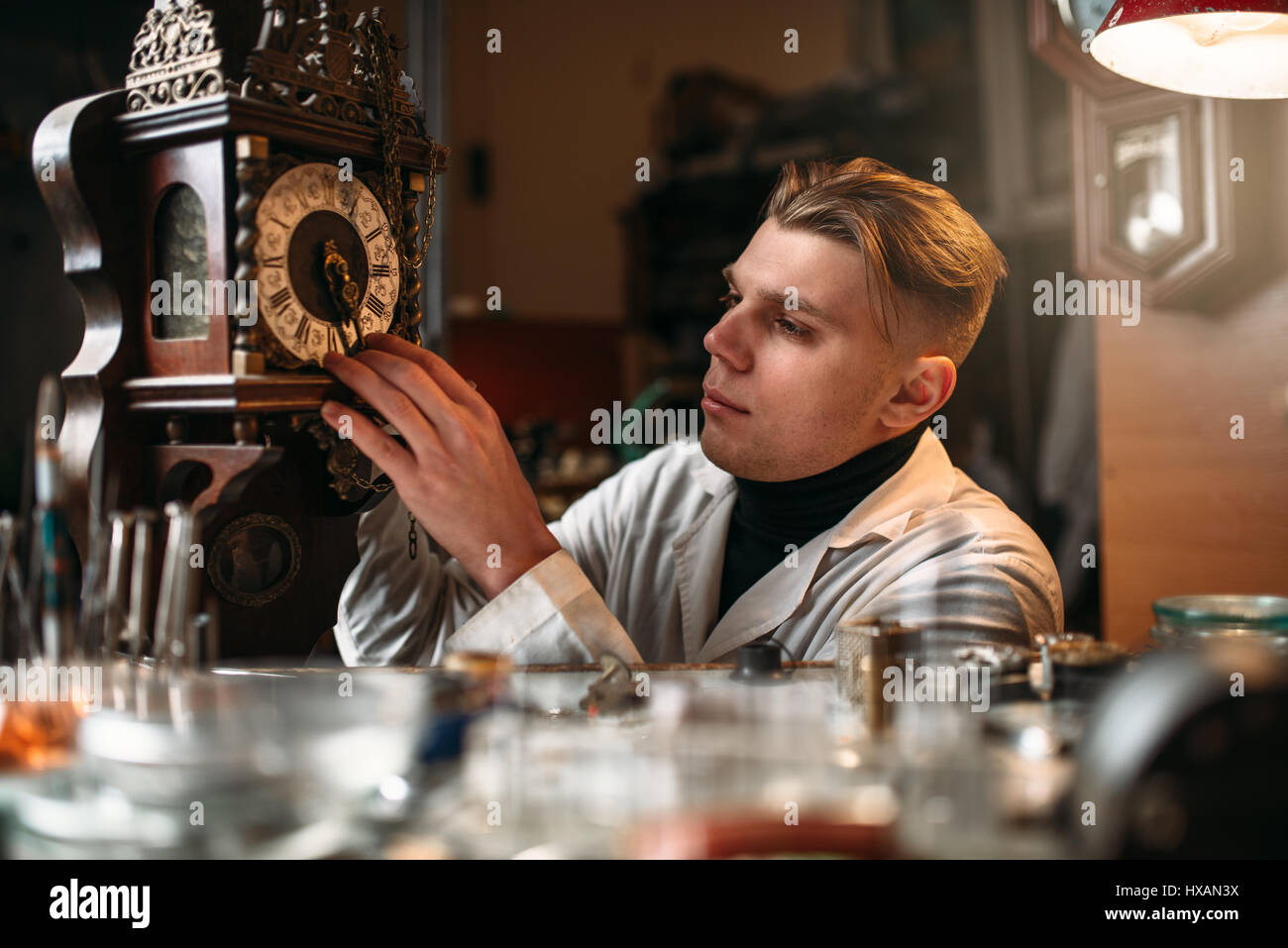 Watchmaker adjusts the mechanism of old wall clock in the workshop ...