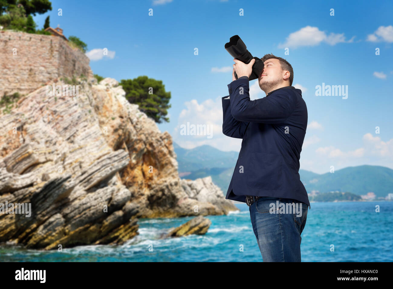 Cameraman in a jacket with digital camera taking picture, rocky coast ...