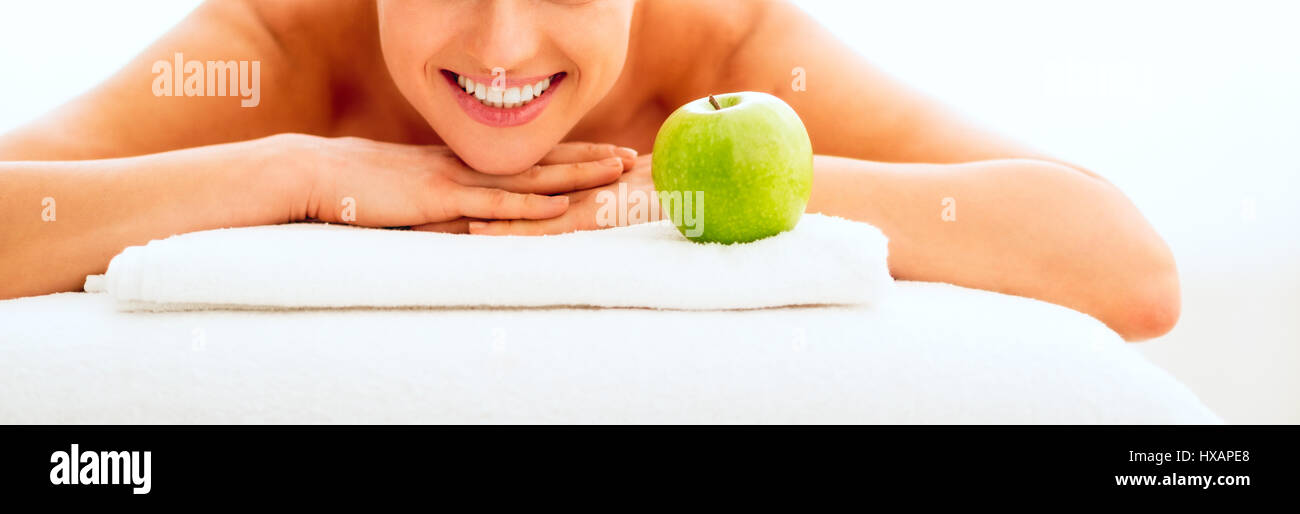 Closeup on smiling young woman with apple laying on massage table Stock ...