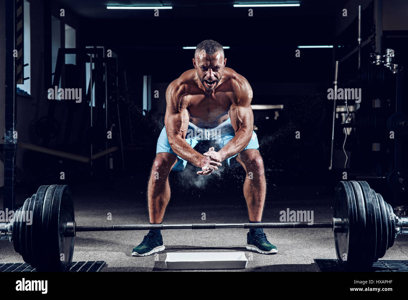Muscular weightlifter clapping hands and preparing for workout at a gym ...