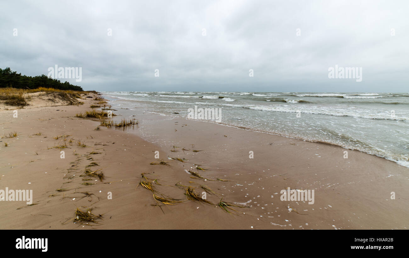 baltic beach in fall with clouds and waves towards deserted dunes ...