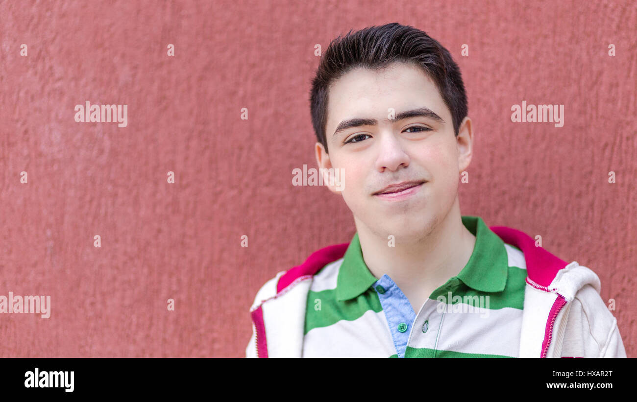 portrait of smiling handsome boy with soft skin on red grunge wall as ...