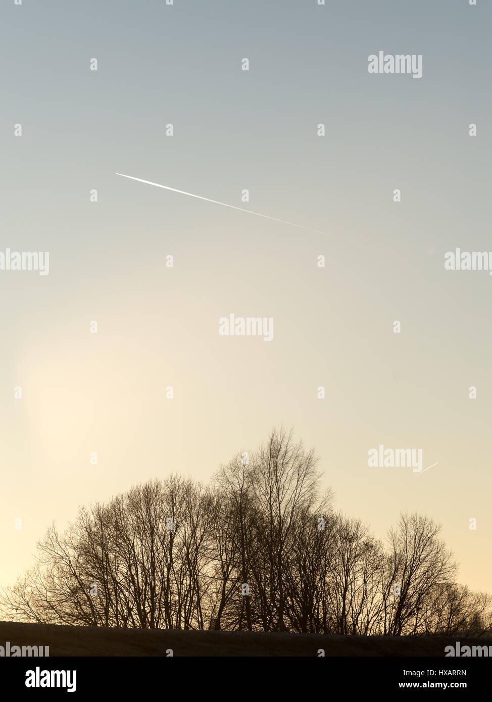 winter sunset with moon and plane trails in the sky Stock Photo - Alamy