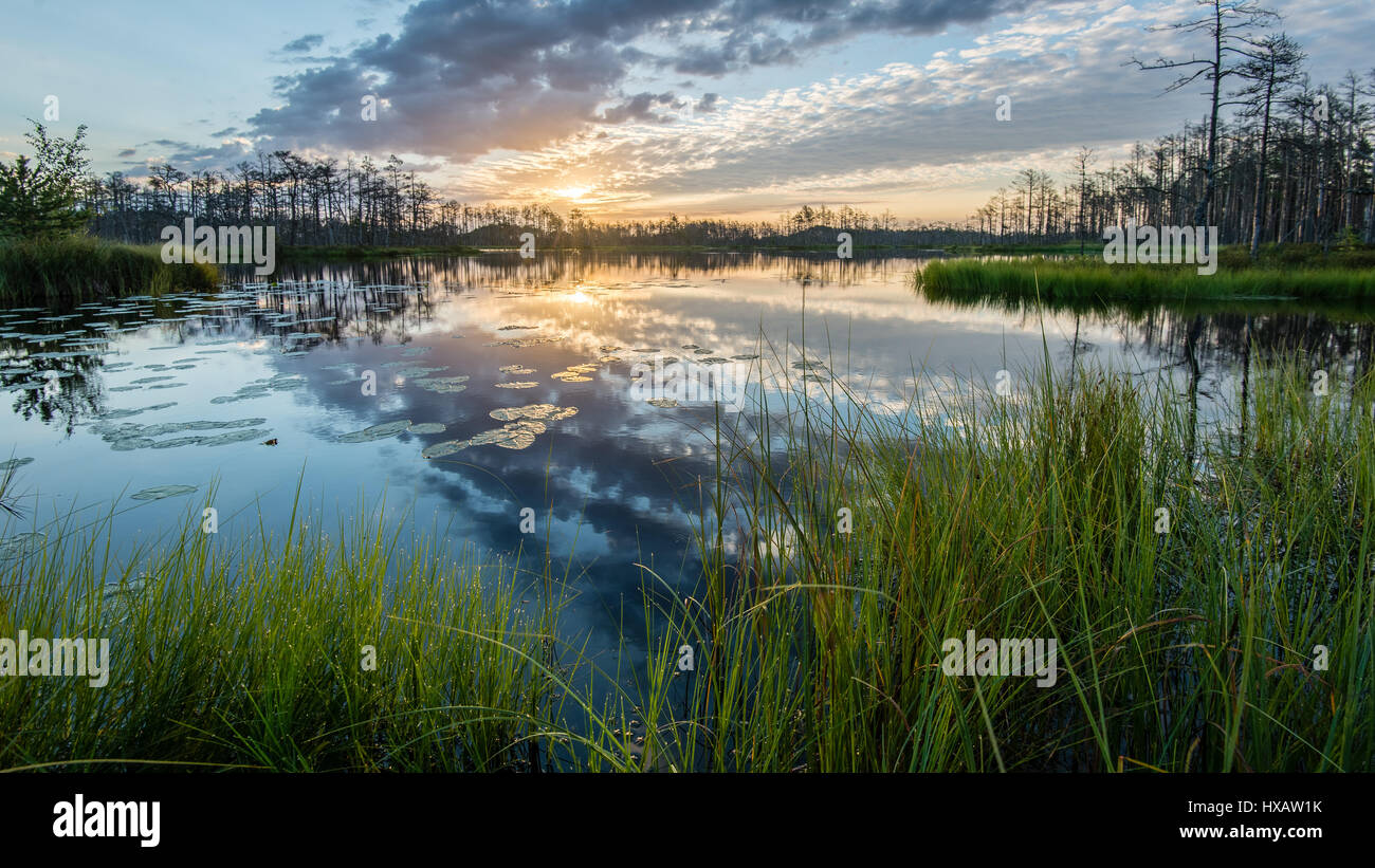 reflections in the lake water at sunrise with clouds and dramatic ...