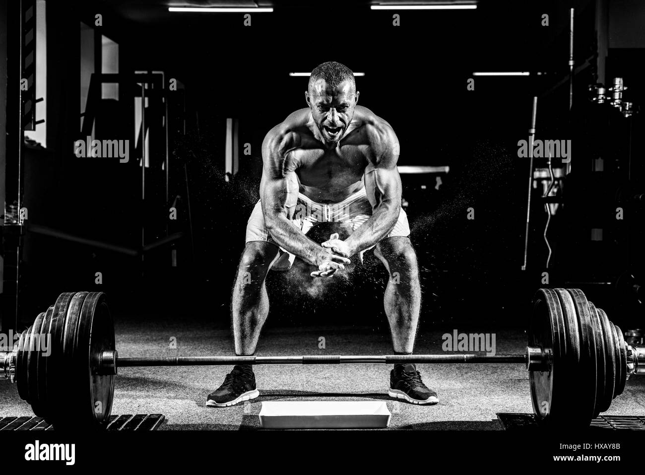 Muscular weightlifter clapping hands and preparing for workout at a gym ...