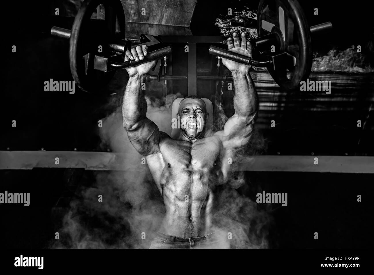 The athlete doing exercises on pectoral muscles in smoke. GYM Stock ...