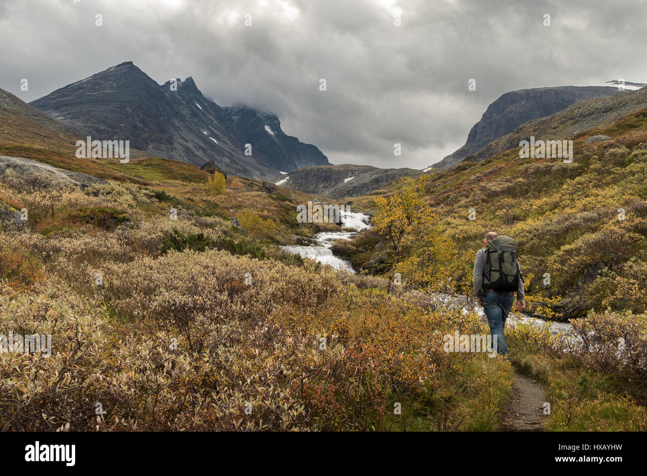 Man walking alone beside river stream towards the mountains of ...