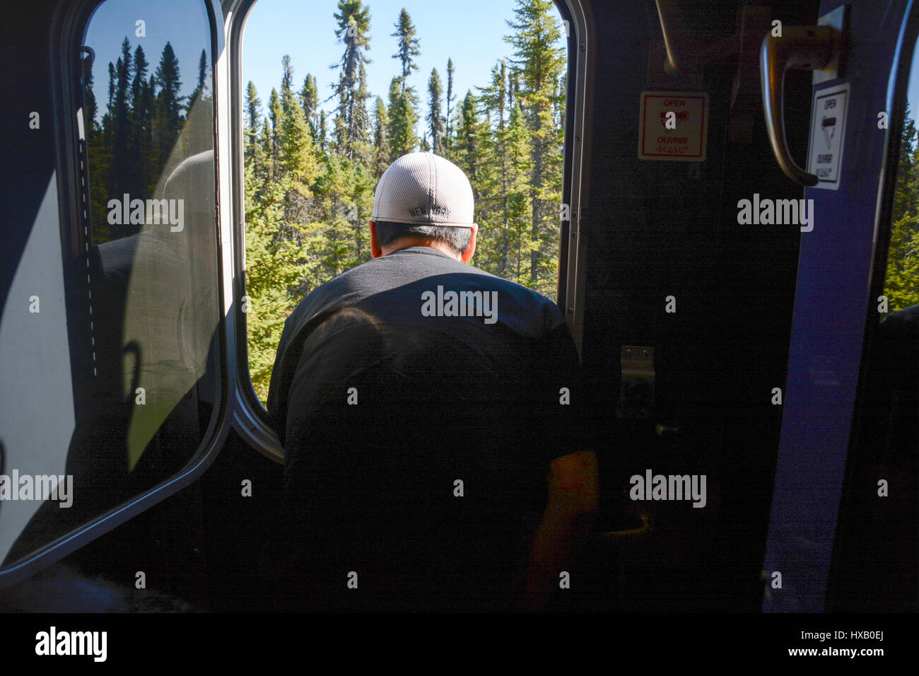 An indigenous Cree man looks out the window of a moving train vestibule ...