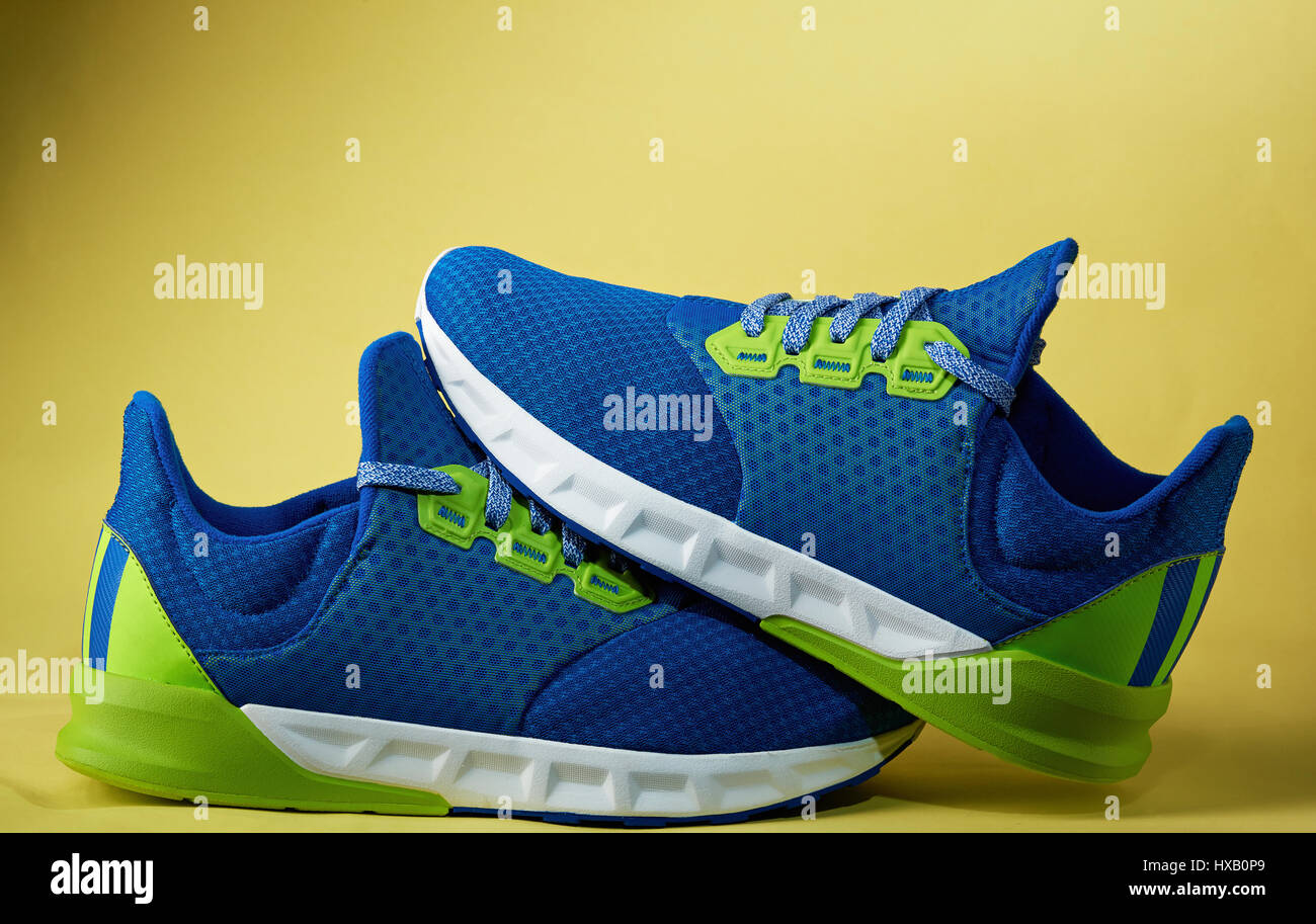 Pair of colorful trainer shoes isolated on yellow background. Blue ...