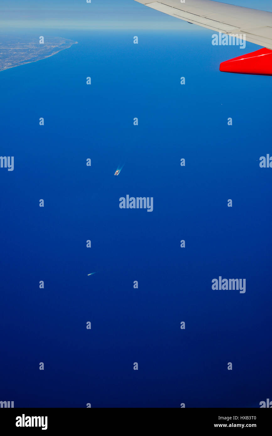 Aerial view of an airplane's wing detail as it flies over blue water ...