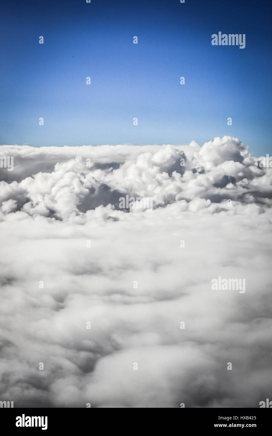 A dramatic aerial view from above the clouds and blue sky horizon from ...