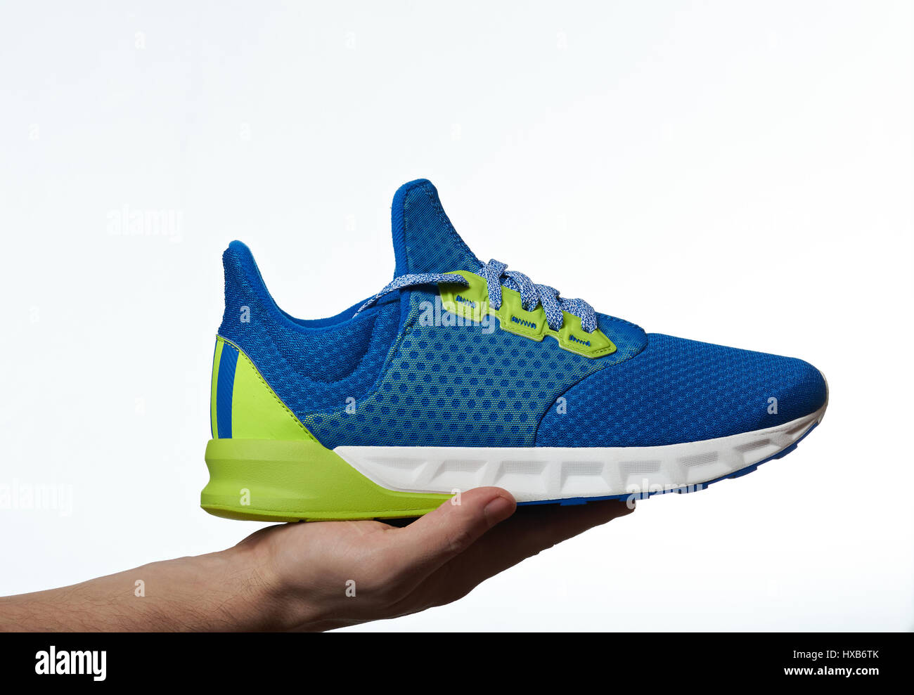Hand hold sport blue colorful shoe closeup isolated on white background ...