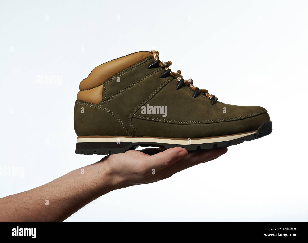 Hand holding hiking shoe isolated on white background. Modern shoe for ...