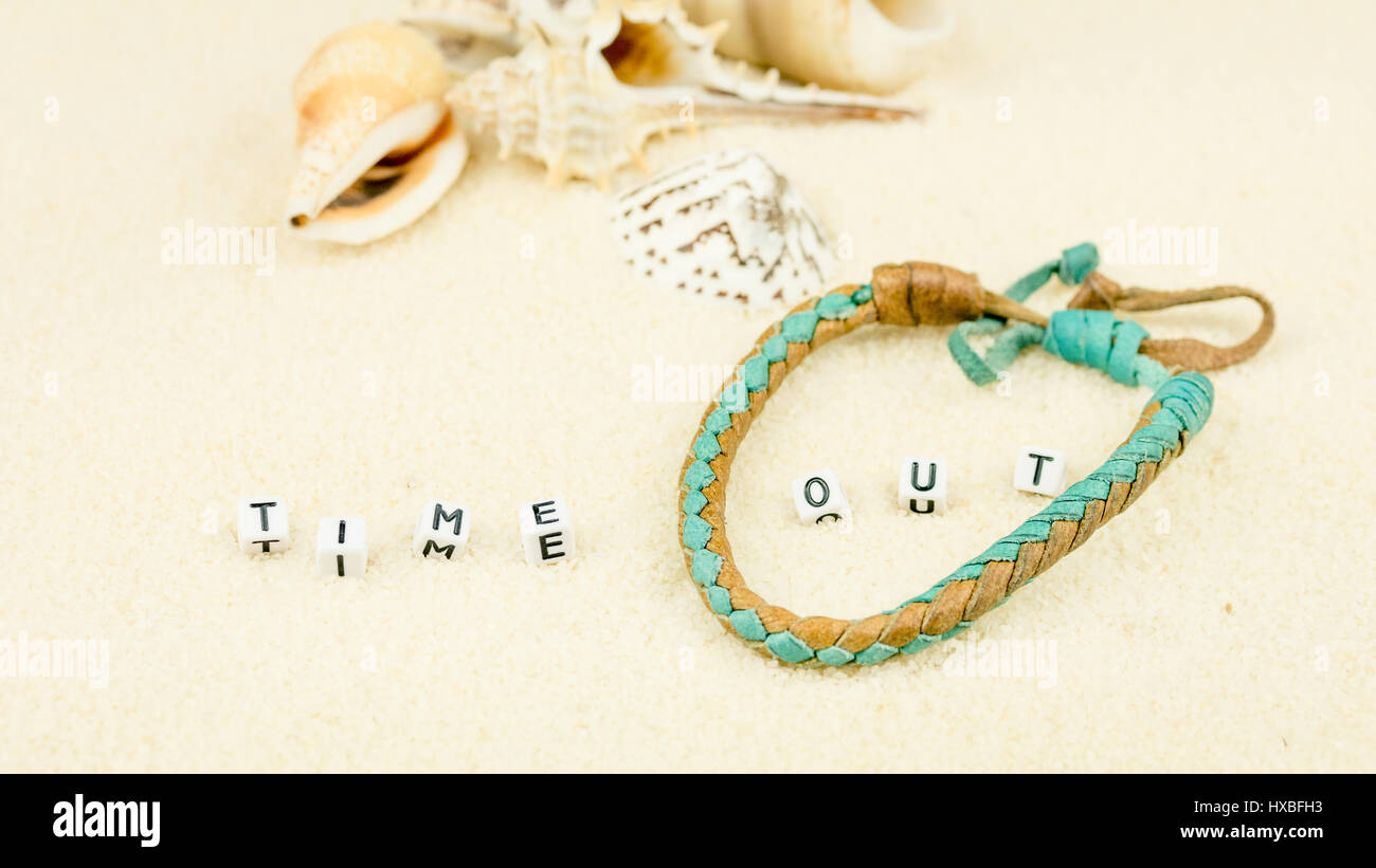 Time out letters in front of sea shells and coloured wristbandon on ...