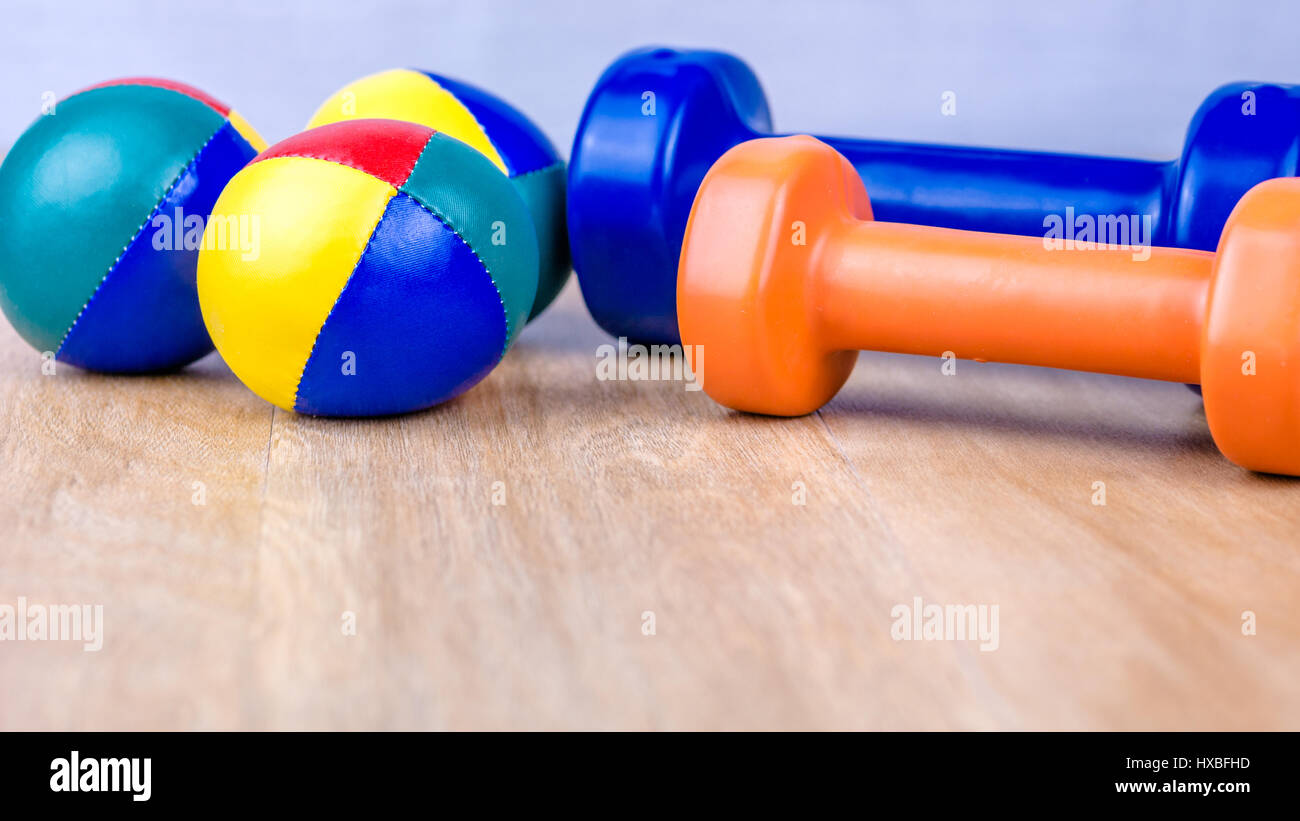 Blue and orange dumbbells and coloured balls on wooden surface Stock ...