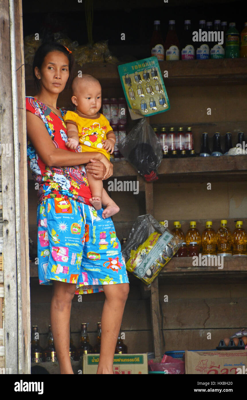 A woman holds her child in the doorway to a shop in the village of ...