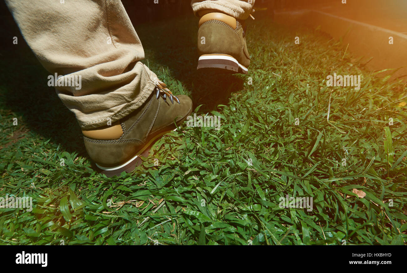 Making step on green grass view from back. Walking away hike shoes ...