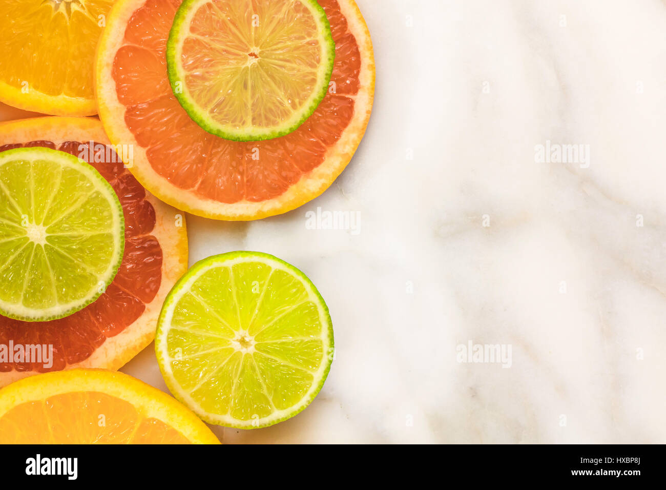 Vibrant juicy citrus fruits on a white marble texture with copy space ...