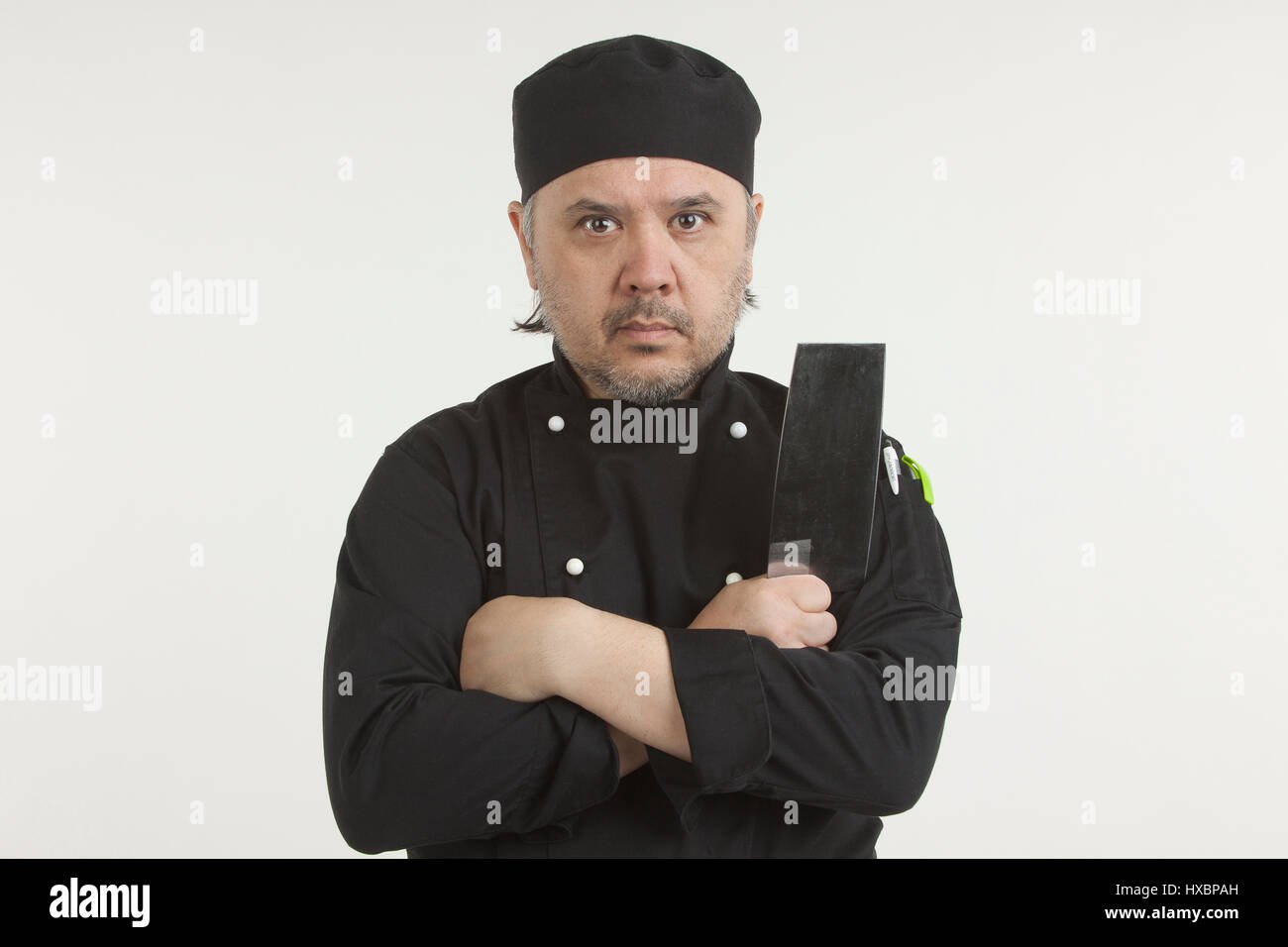 Chef Asian Senior arms folded holding meat cleaver with intense look ...
