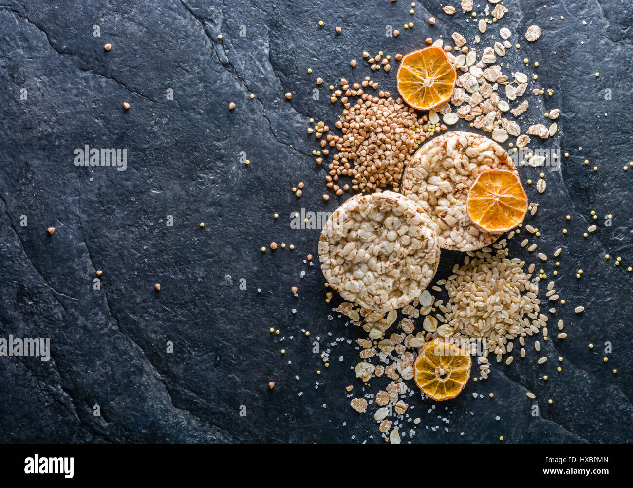 Round Crisp on a black stone background. Rice grains, oatmeal flakes ...