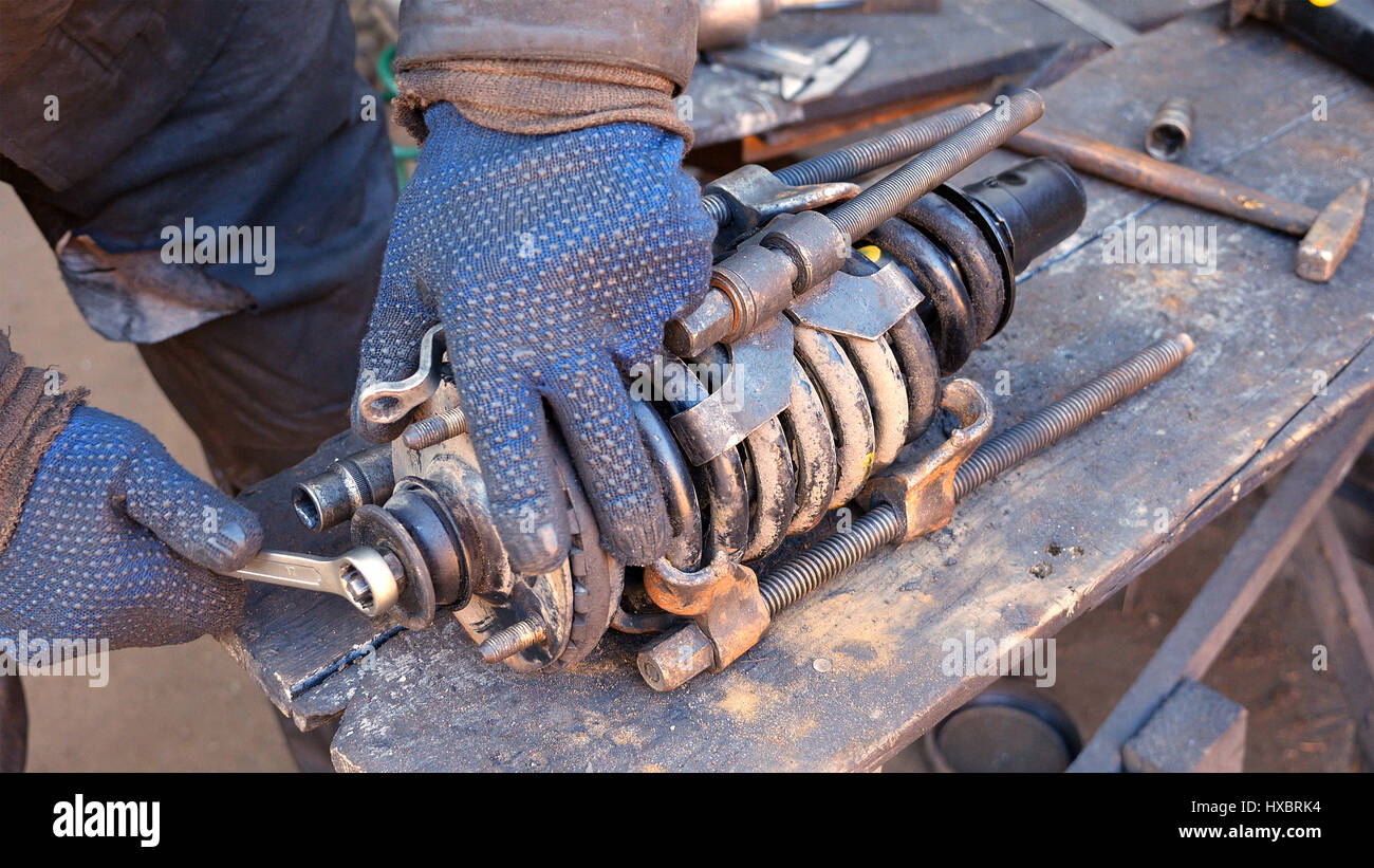 Auto mechanic working on shock absorber in garage Stock Photo - Alamy