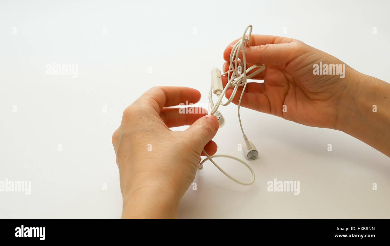 Woman untangles tangled earbuds or earphone knot Stock Photo - Alamy