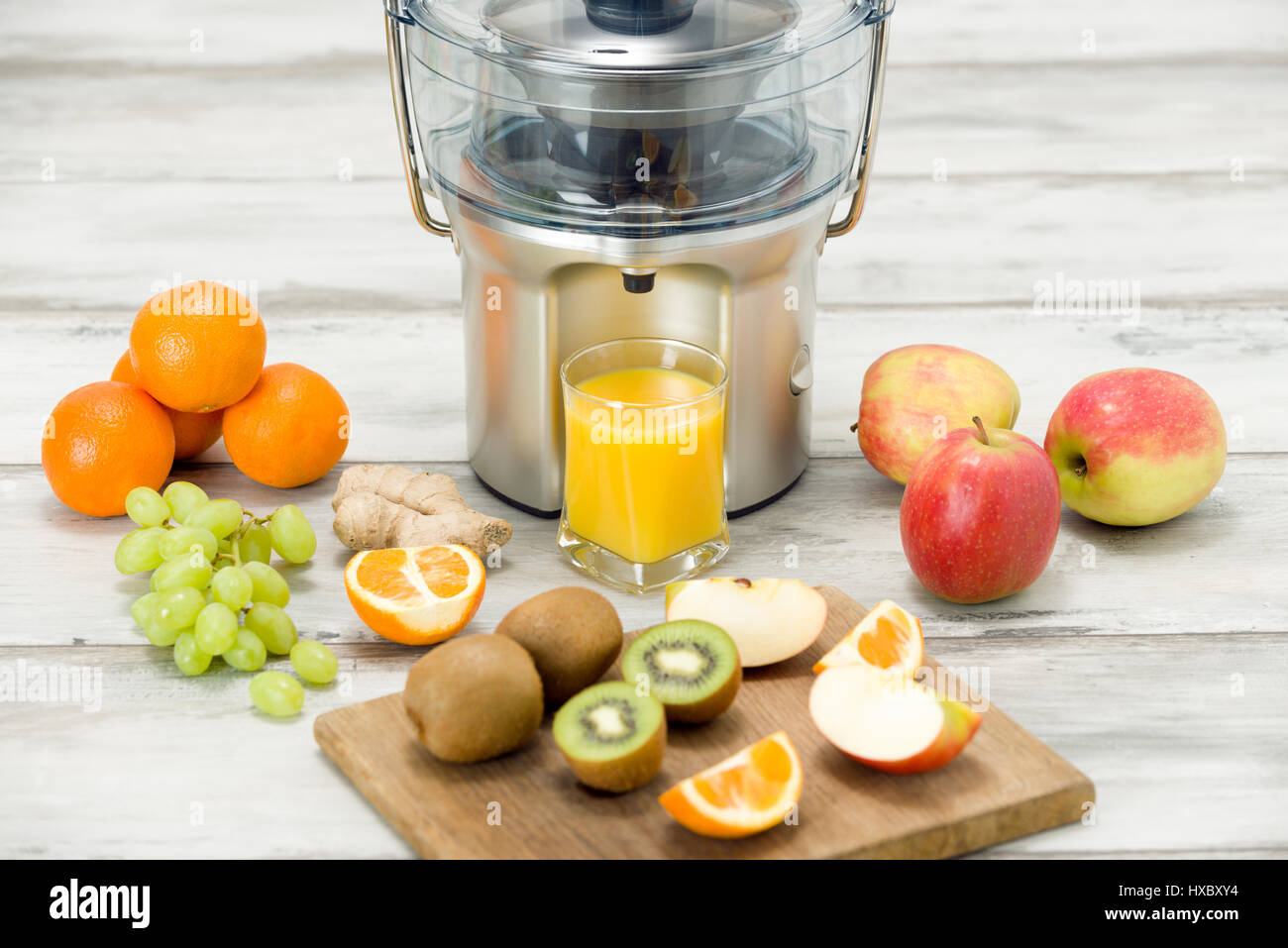 Modern electric juicer, various fruit and glass of freshly made juice ...