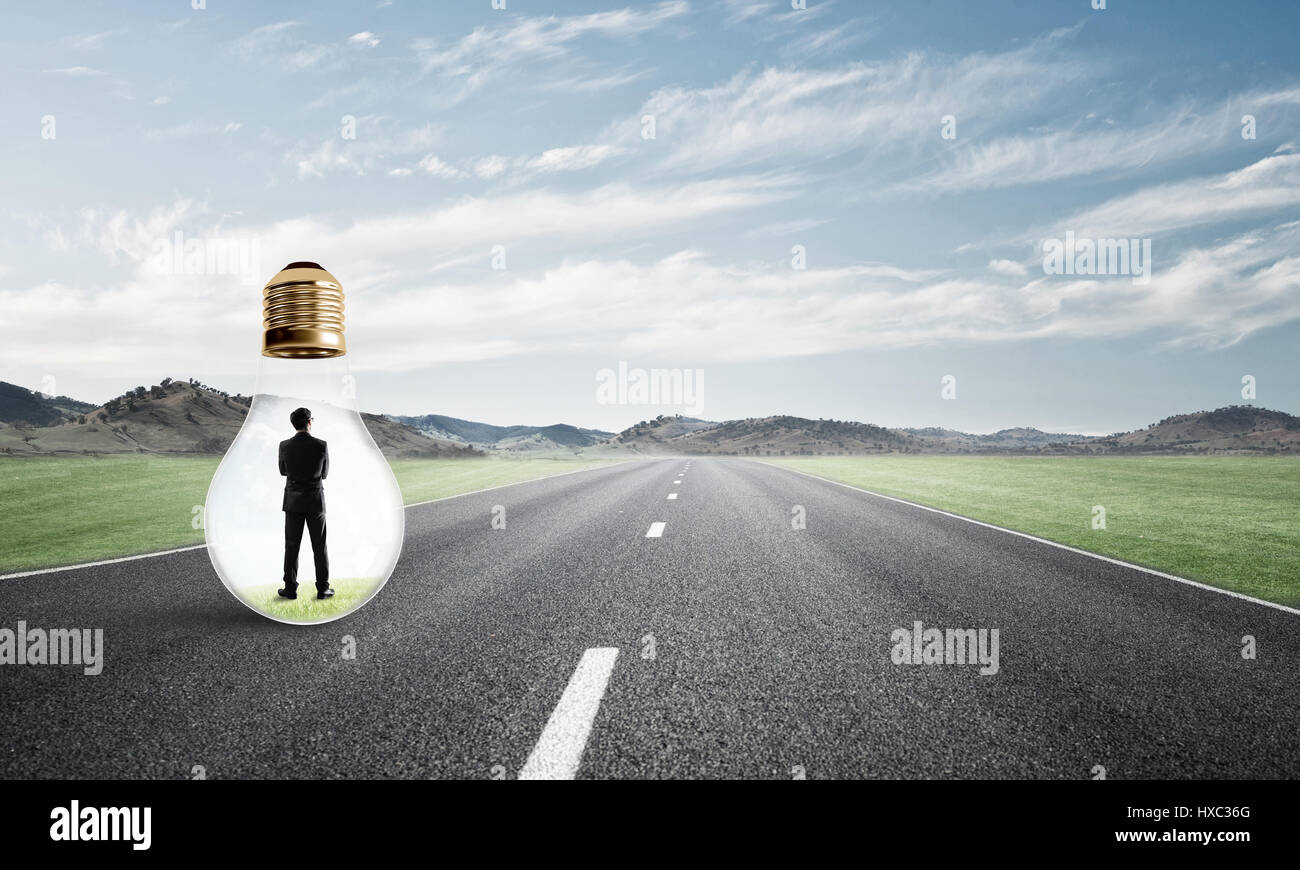 Young businessman trapped inside of light bulb on asphalt road Stock ...
