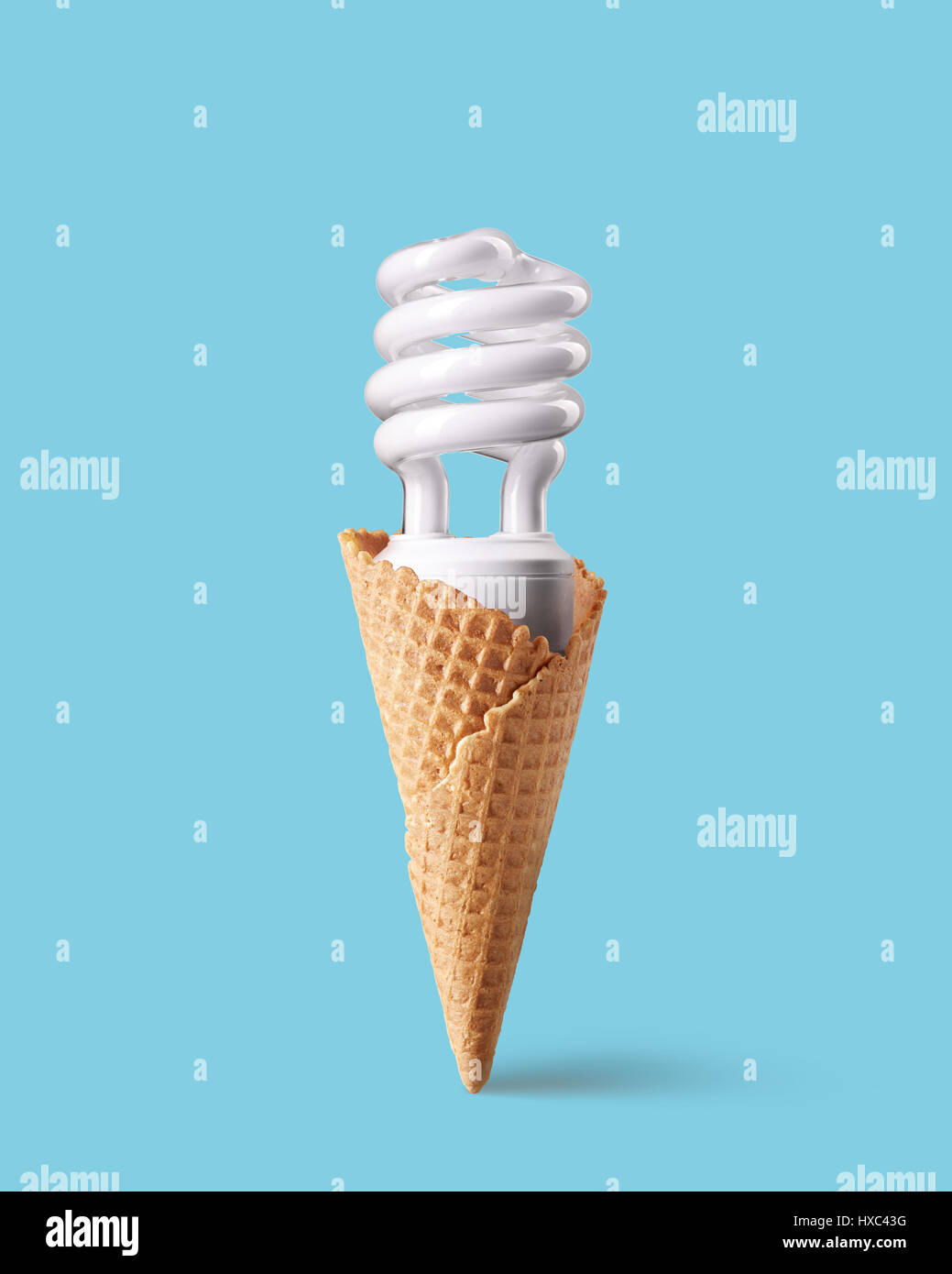 Compact fluorescent bulb in ice cream cone on blue background. Ice ...