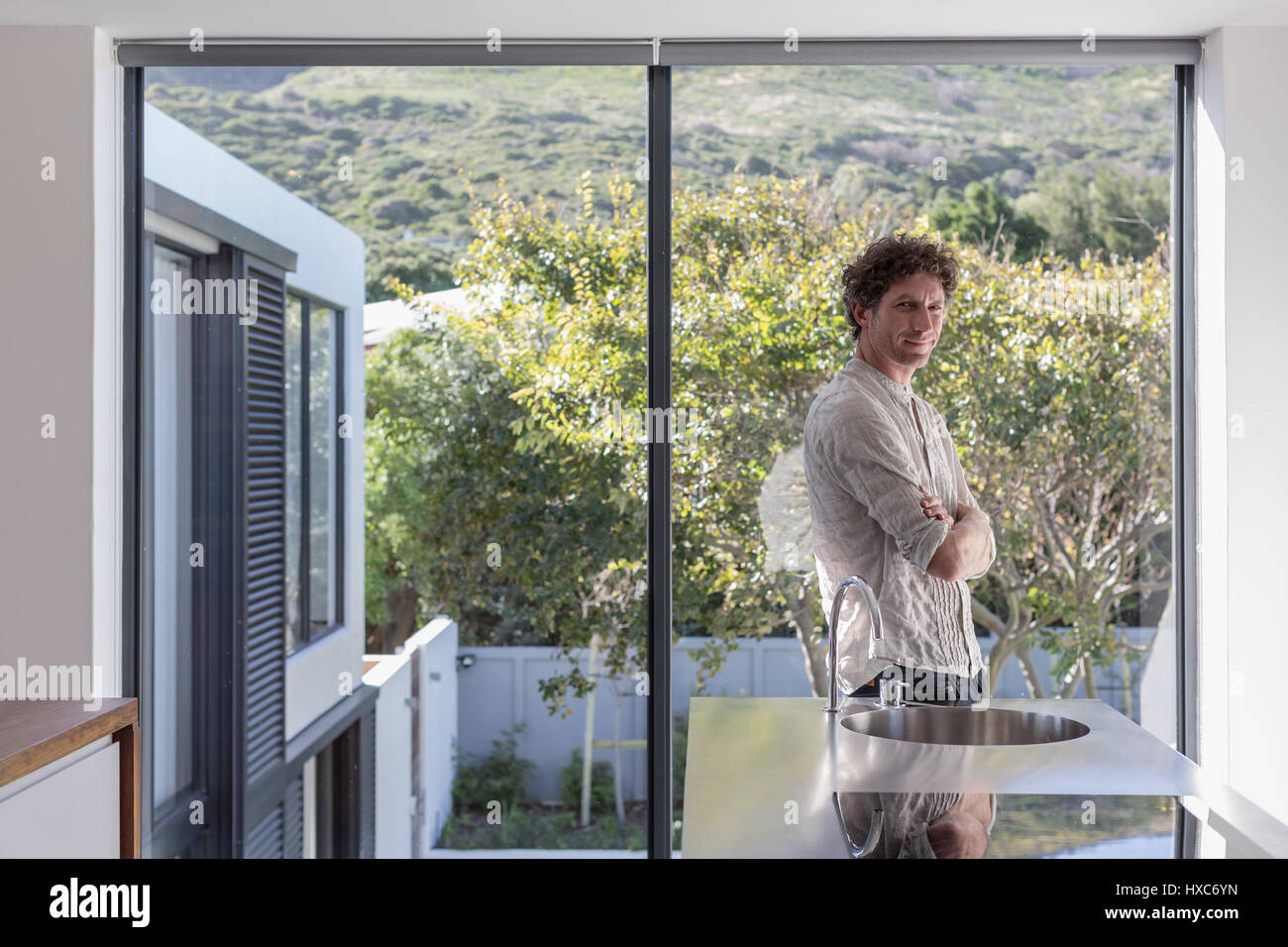 Portrait confident man in sunny modern home showcase interior kitchen ... Portrait confident man in sunny modern home showcase interior kitchen ...