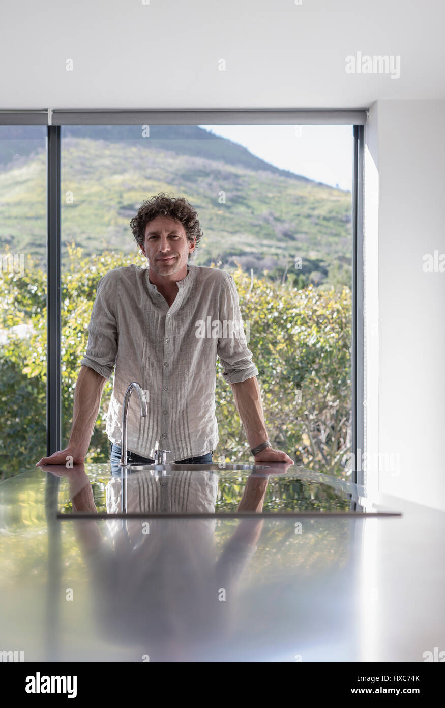Portrait smiling man leaning on counter in sunny kitchen Stock Photo ...