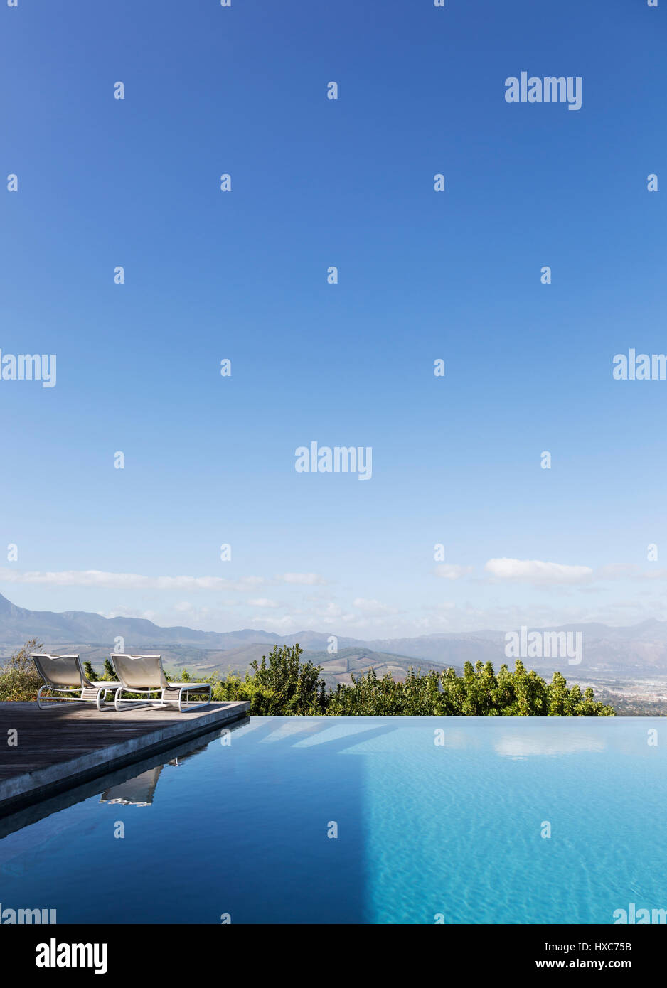 Tranquil luxury infinity pool with mountain view below sunny blue sky ...