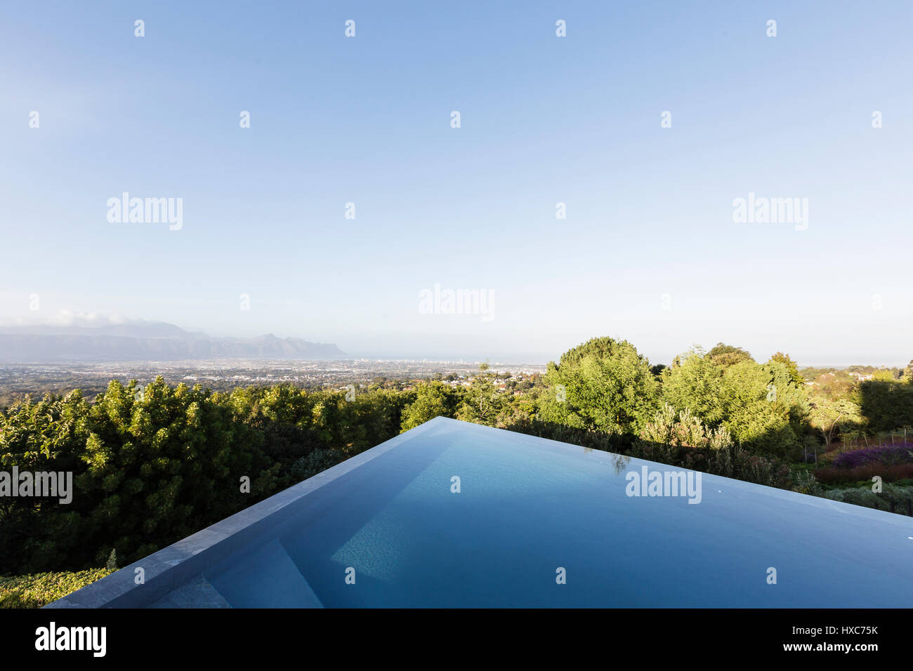 Modern, geometric infinity pool with sunny view under blue sky Stock ...