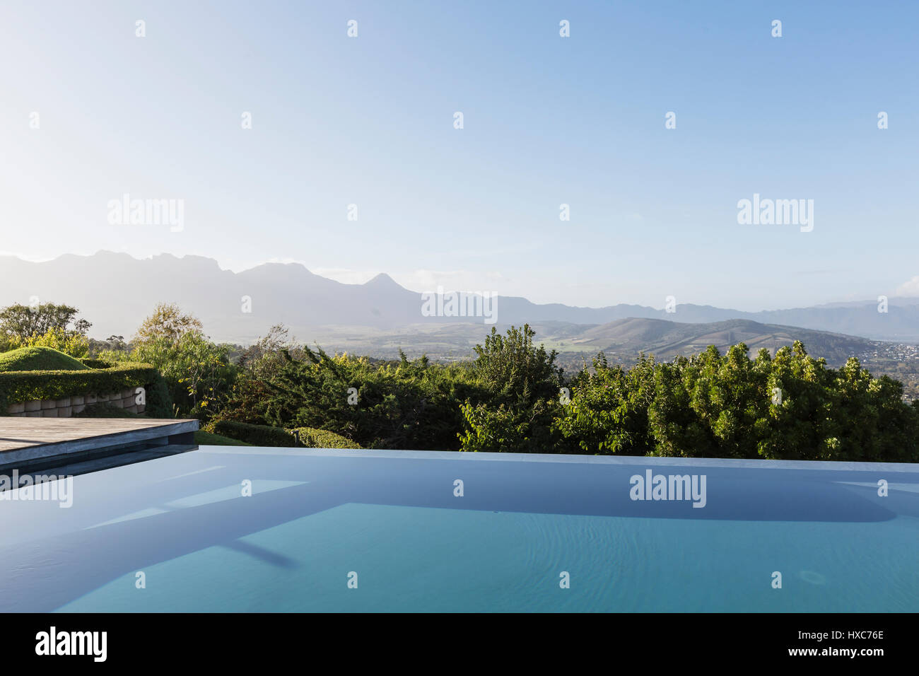 Tranquil luxury infinity pool with mountain view below sunny blue sky ...