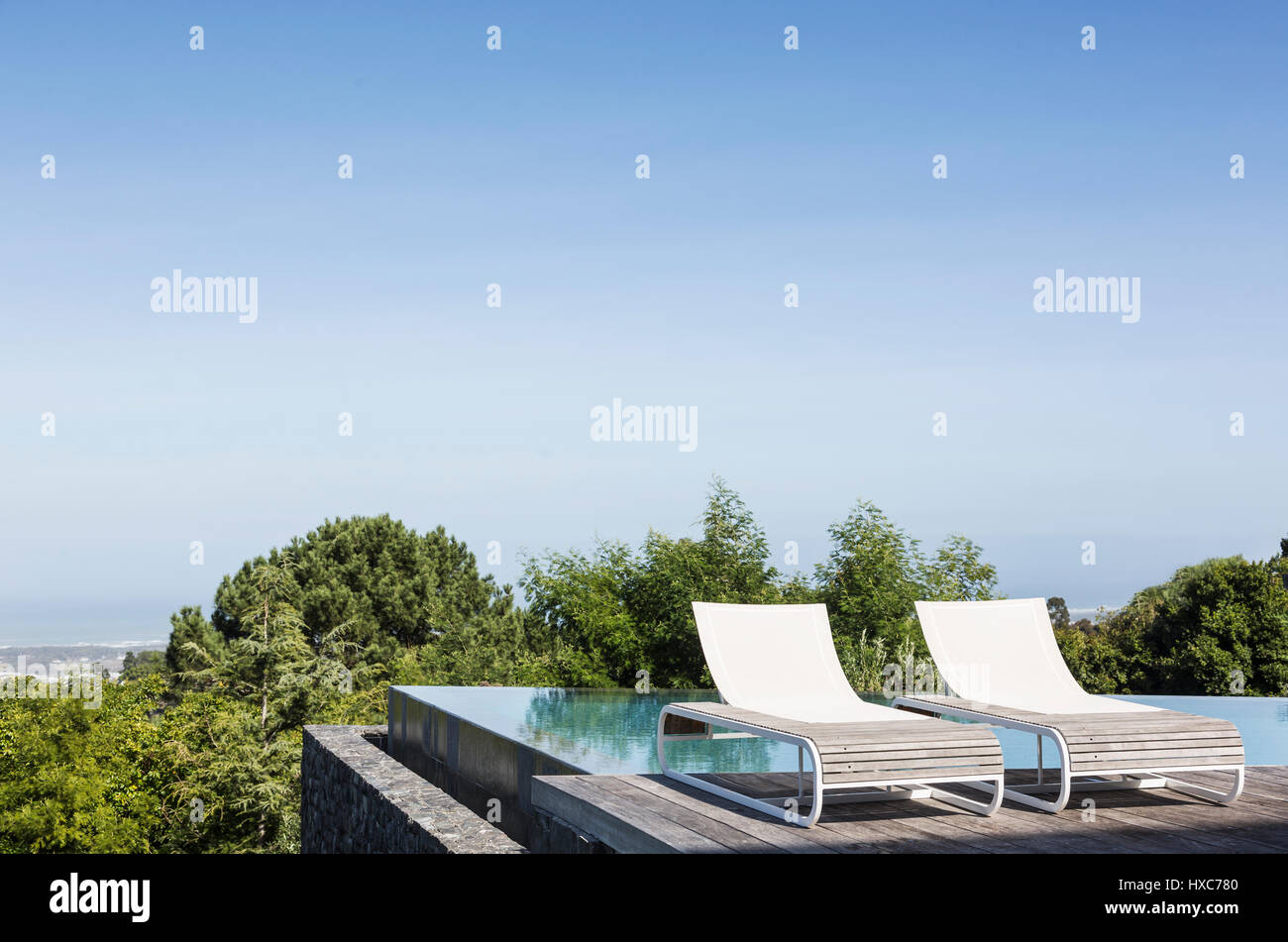 Lounge chairs and infinity pool under tranquil, sunny blue sky Stock ...