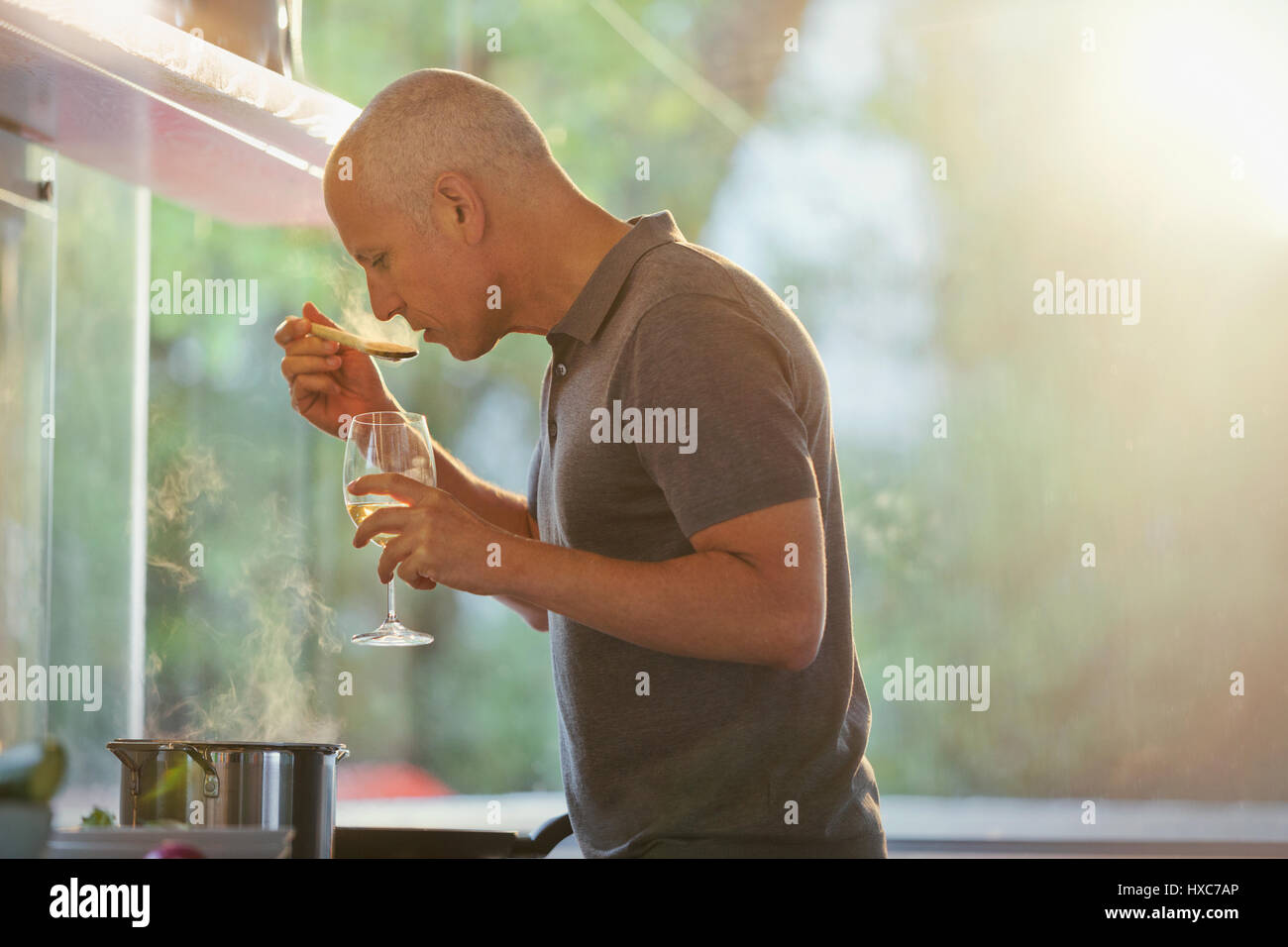 Man drinking white wine and cooking at stove in kitchen Stock Photo - Alamy