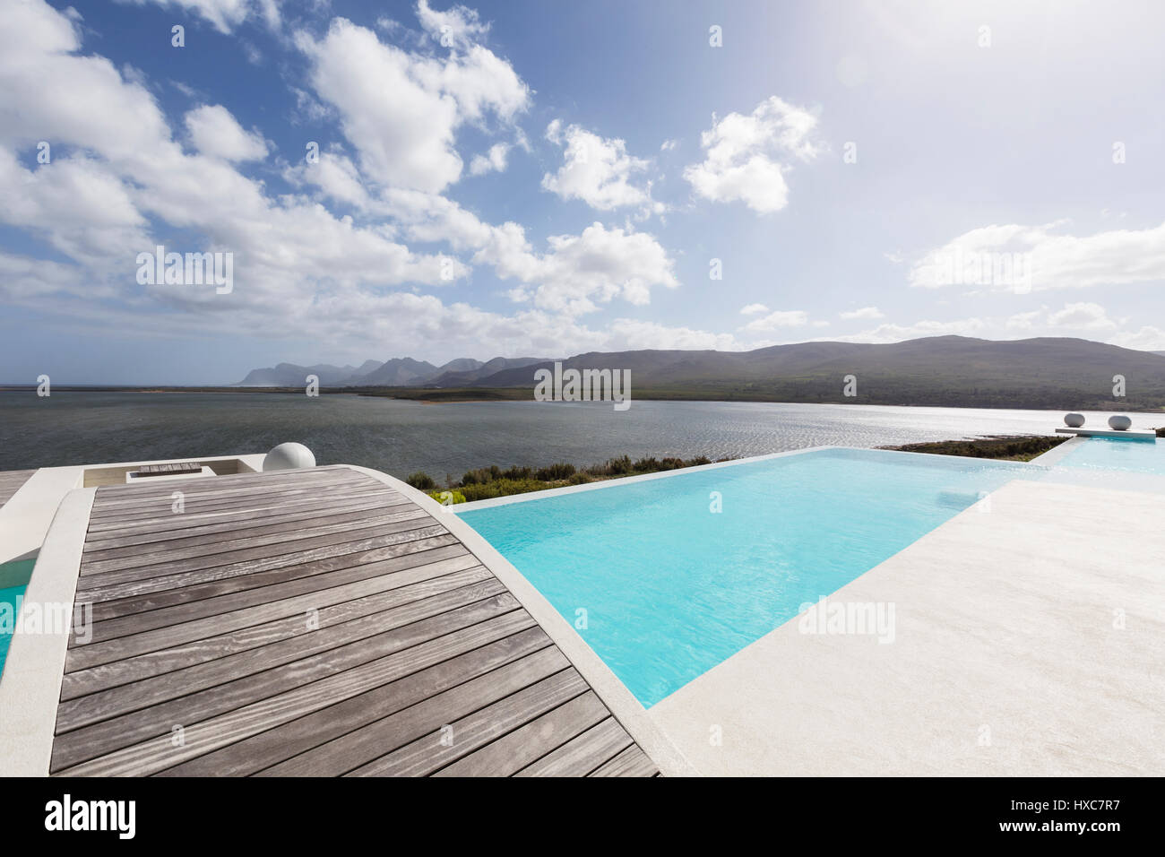 Sunny modern luxury infinity pool with footbridge and ocean view Stock ...