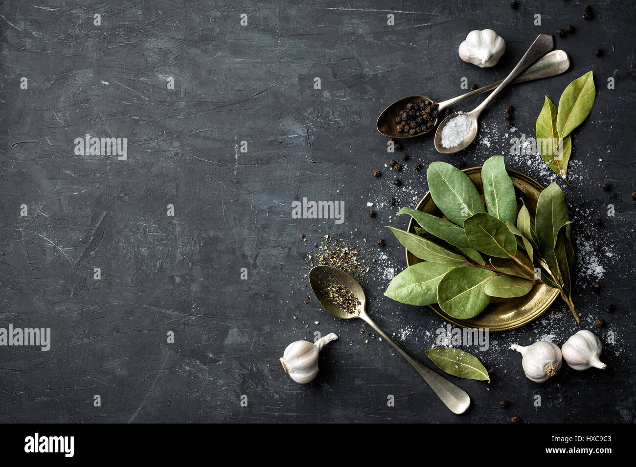 Dark culinary background with bay leaves, salt, pepper and garlic, view ...