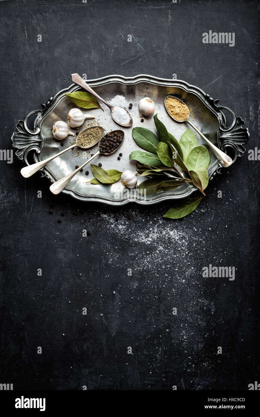 Dark culinary background with bay leaves, salt, pepper and garlic Stock ...