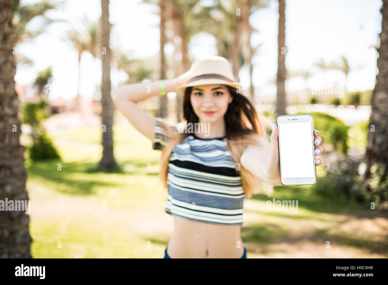 Woman pointed phone with white screen on camera on palms background ...