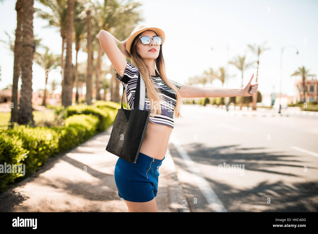 Travel woman hitchhiking. Beautiful female hitchhiker by the road ...