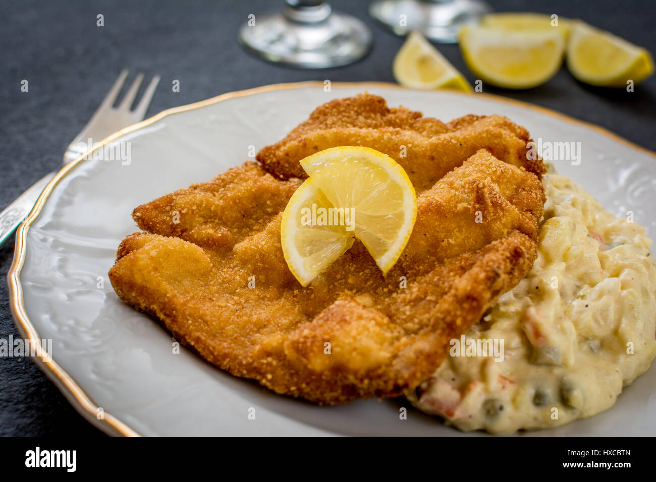 Pork fried schnitzel with traditional potato salad on black stone table ...
