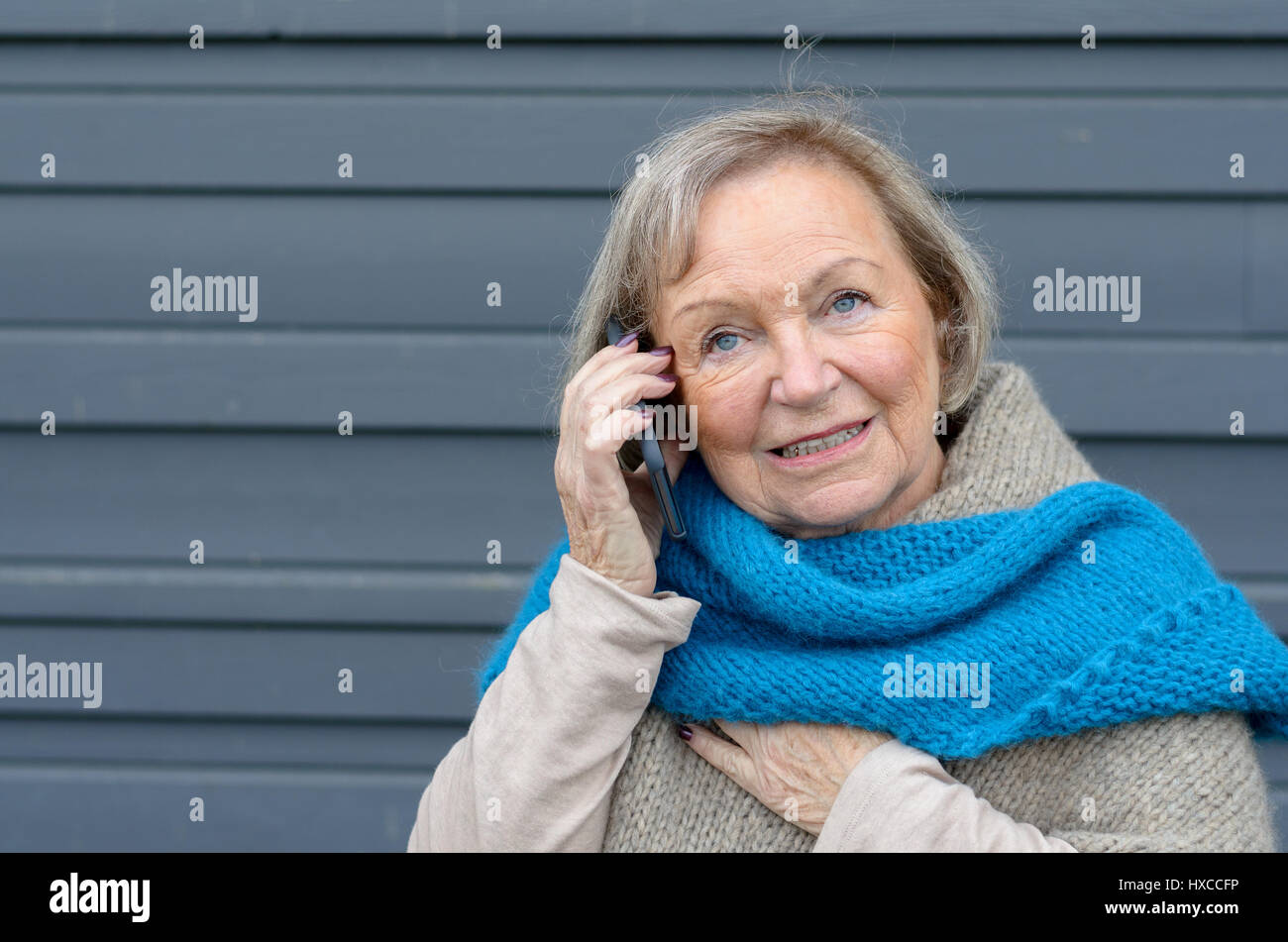 Attractive elderly woman talking on her mobile phone looking up into ...