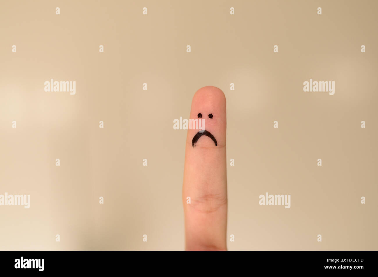 Unhappy, sad or depressed face hand drawn on a finger tip isolated on a ...