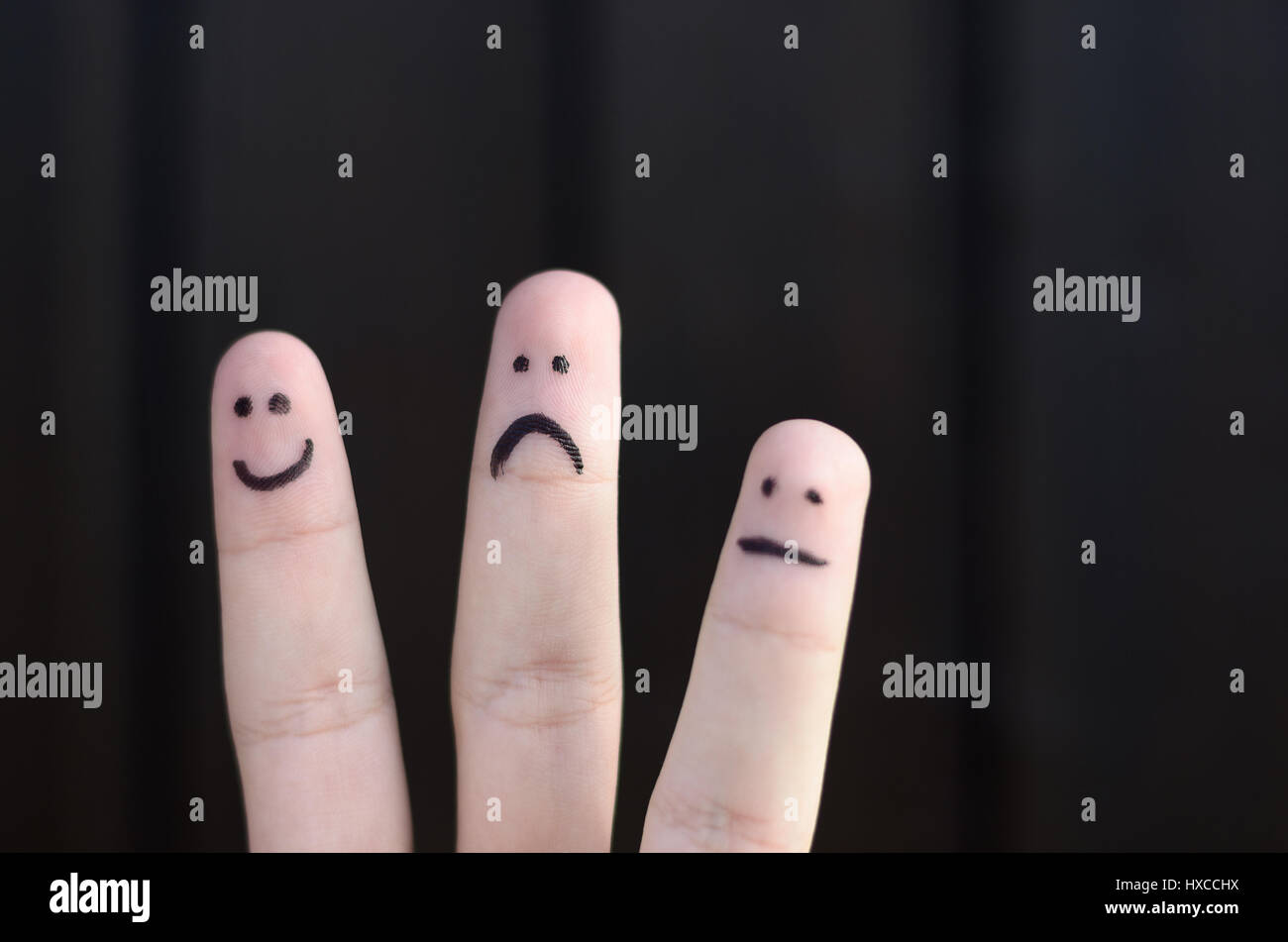 Three different emoticons hand drawn on fingers with a black marker pen ...