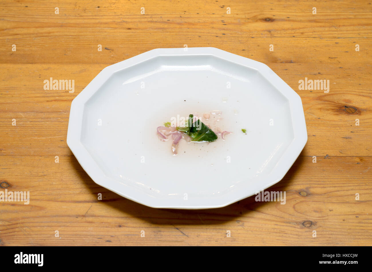 Empty plate after eating salad on a wood table Stock Photo - Alamy