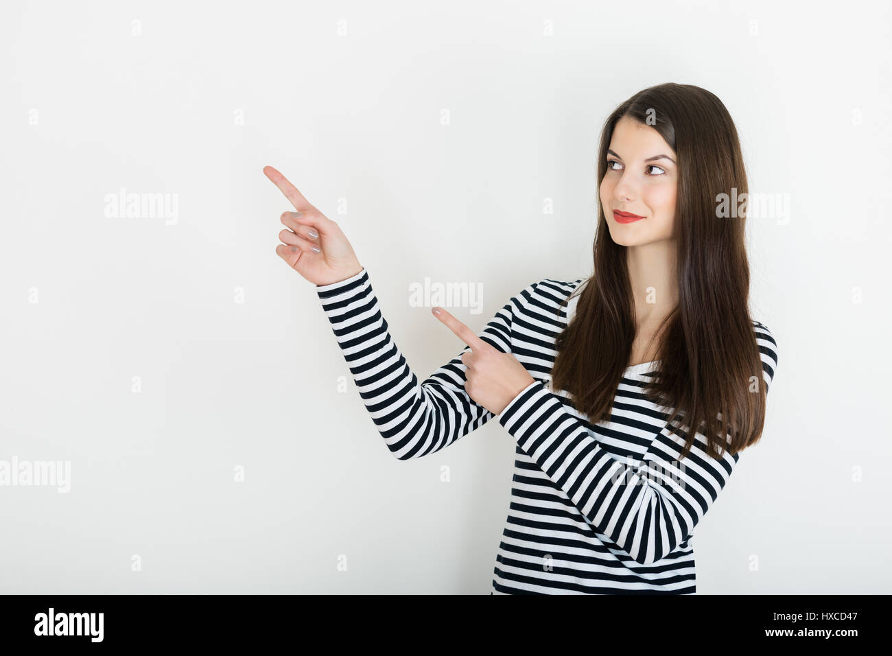 Beautiful girl pointing to the side. Presenting your product. Isolated ...