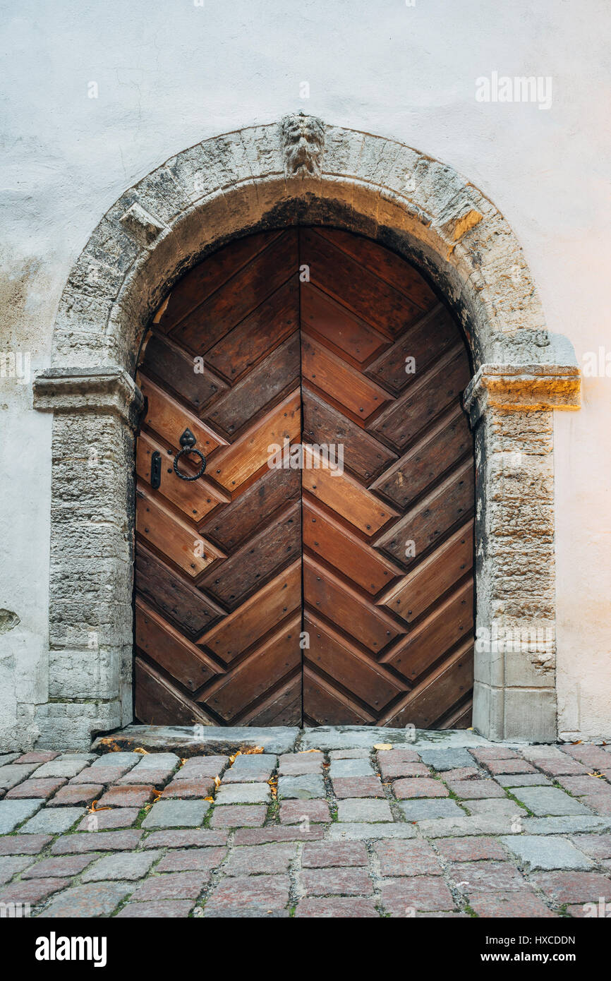 Medieval style wooden door with stone arch in old building on paved ...